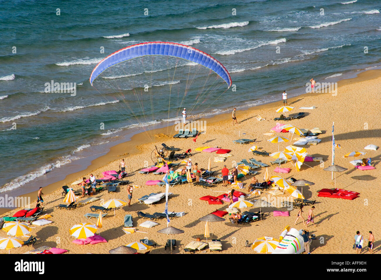 Powered paraglider flying over people enjoying the sun aerial Burc ...