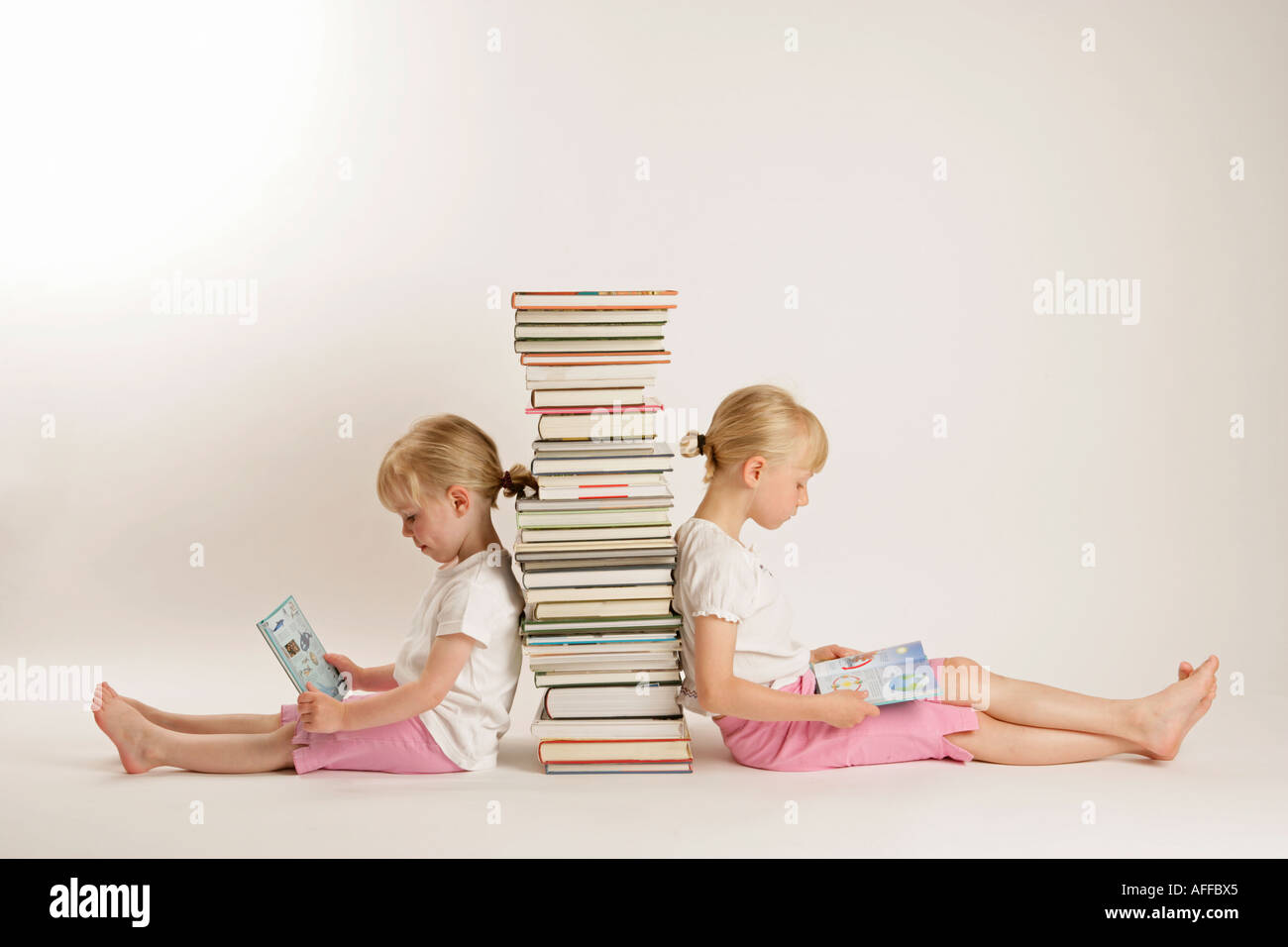 Pair of girls reading books Two girls sitting by a stack of books Stock ...