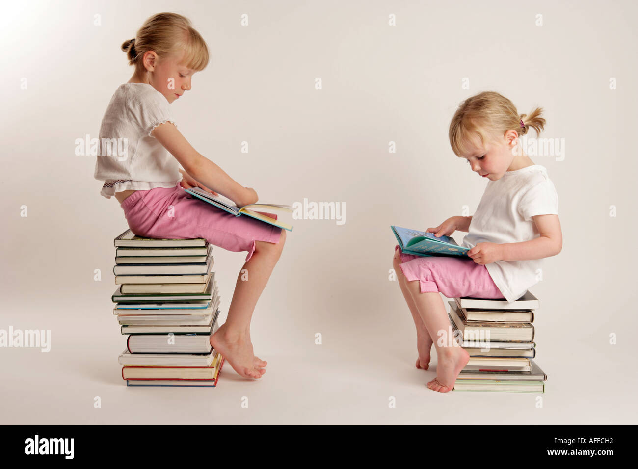 Two girls reading books Two girls sitting on a pile of books reading ...