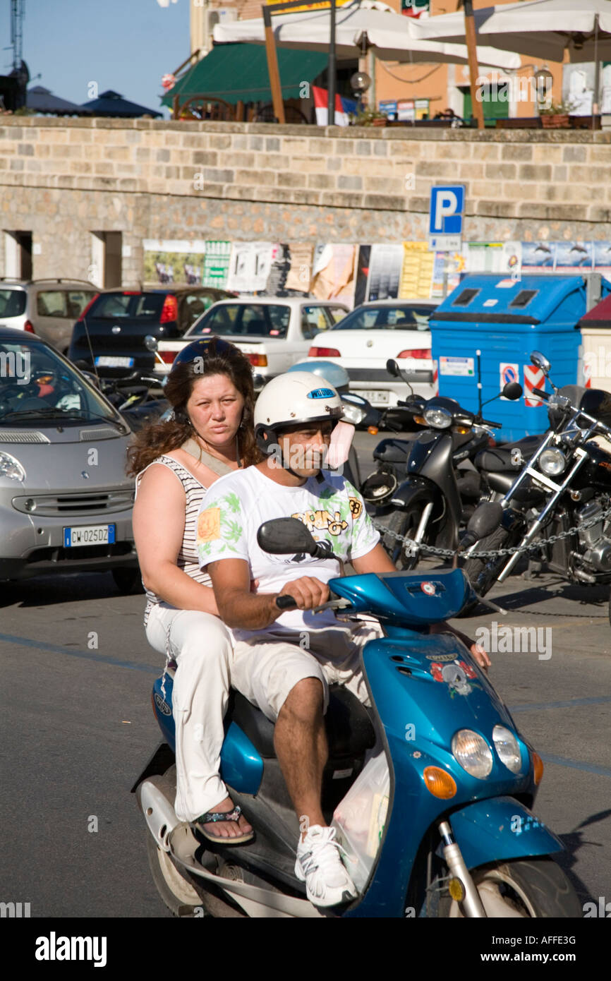 Couple riding moped in Porto Santo Stefano Monte Argentario Tuscany ...