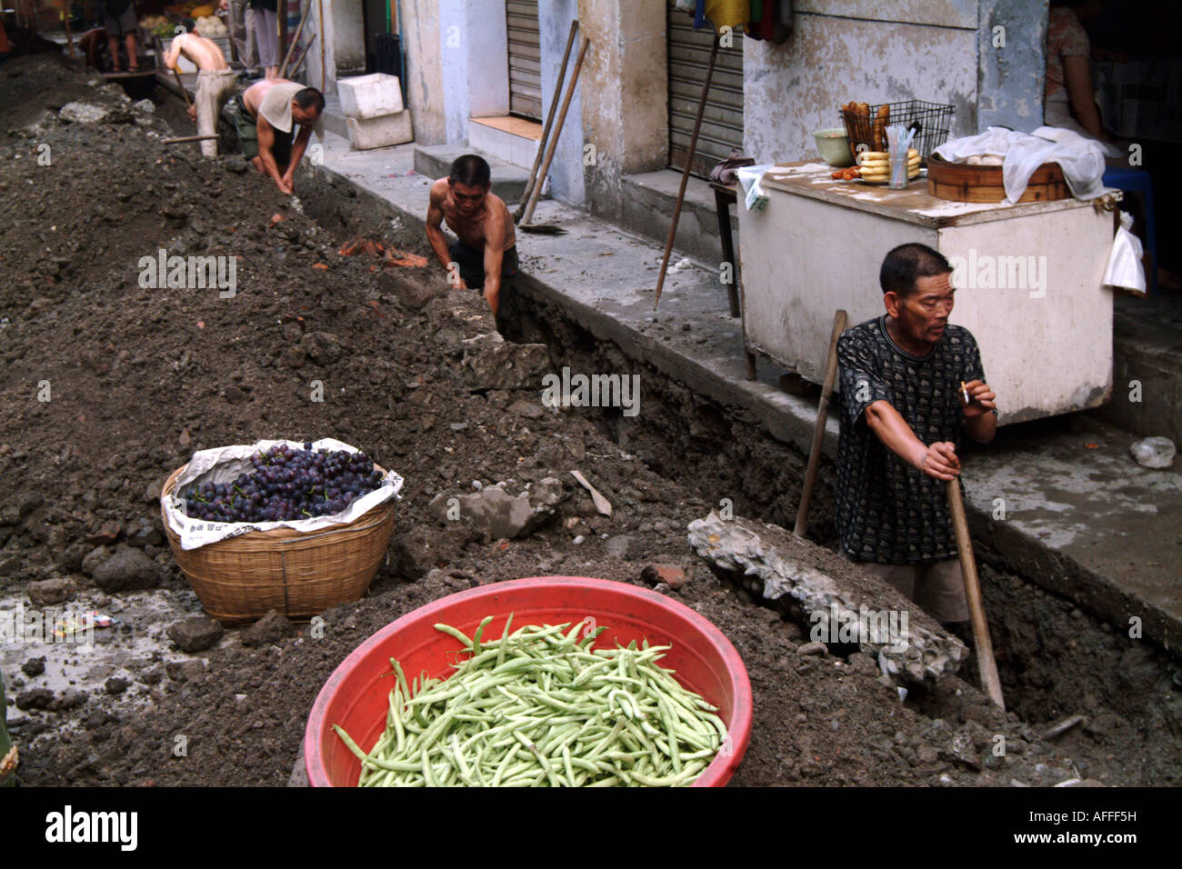 Workmen dig up a back street that is usually a food market in Kunming ...