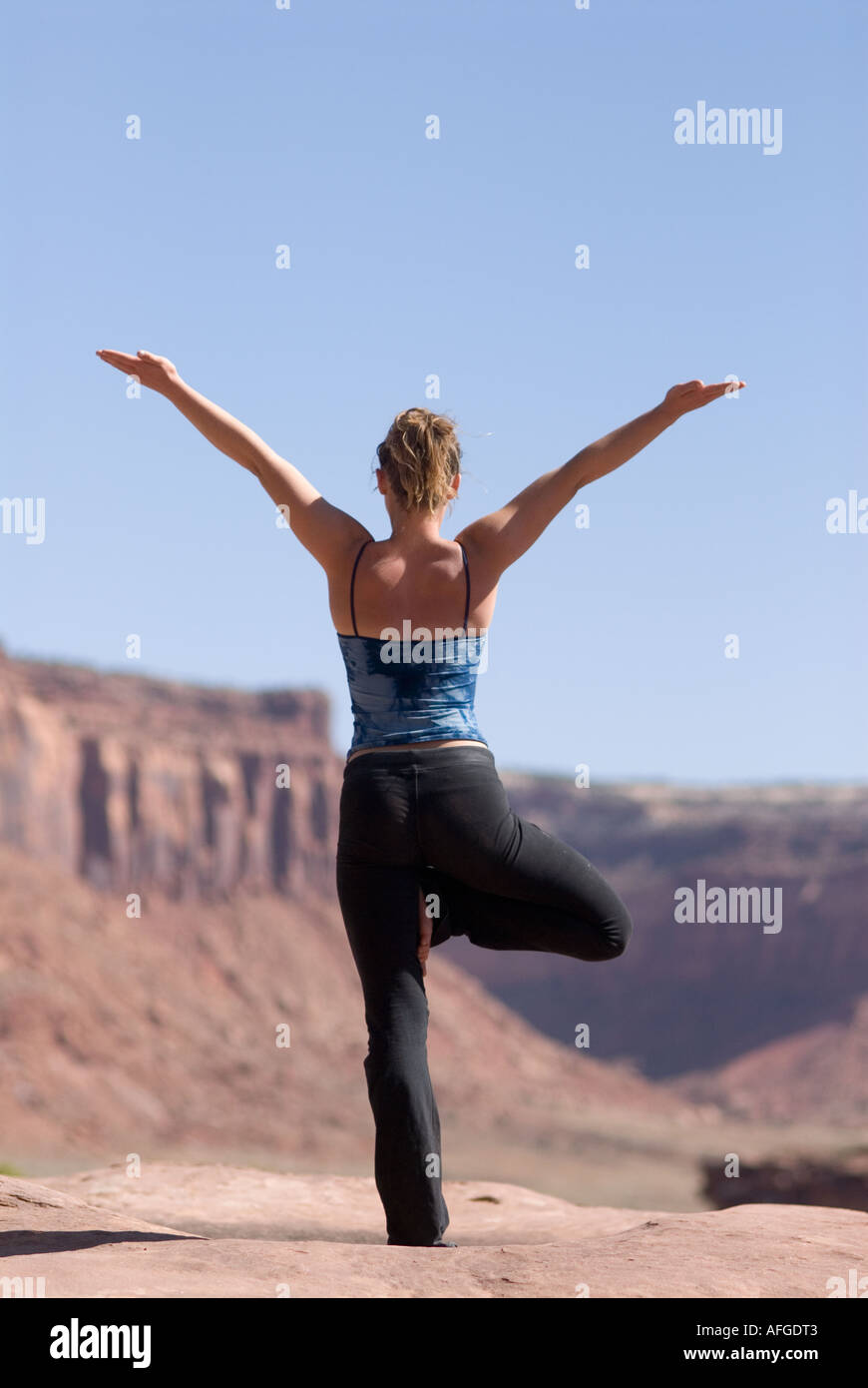 Young woman doing a yoga pose in the canyonlands, while overlooking a ...