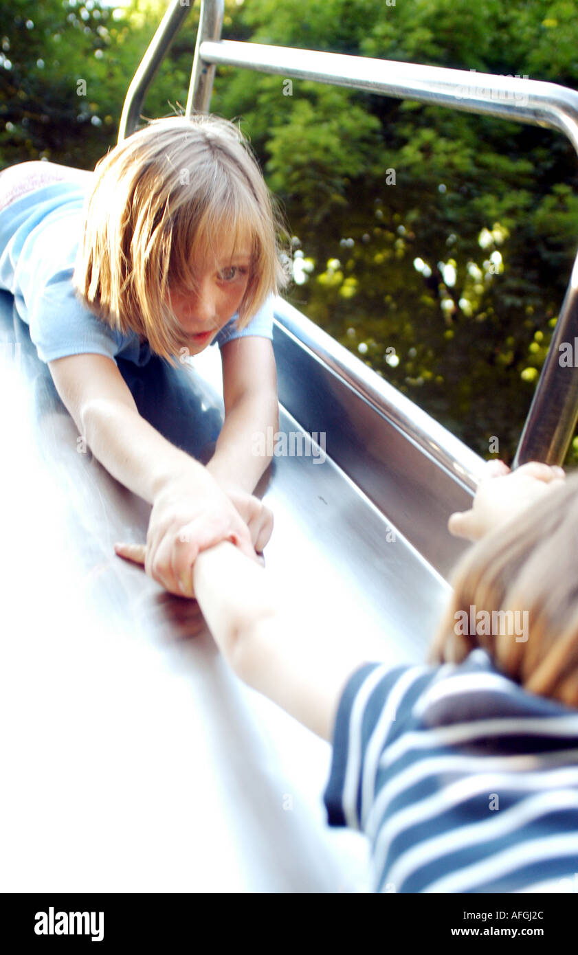 Kids helping each other on a slide, portrait Stock Photo - Alamy