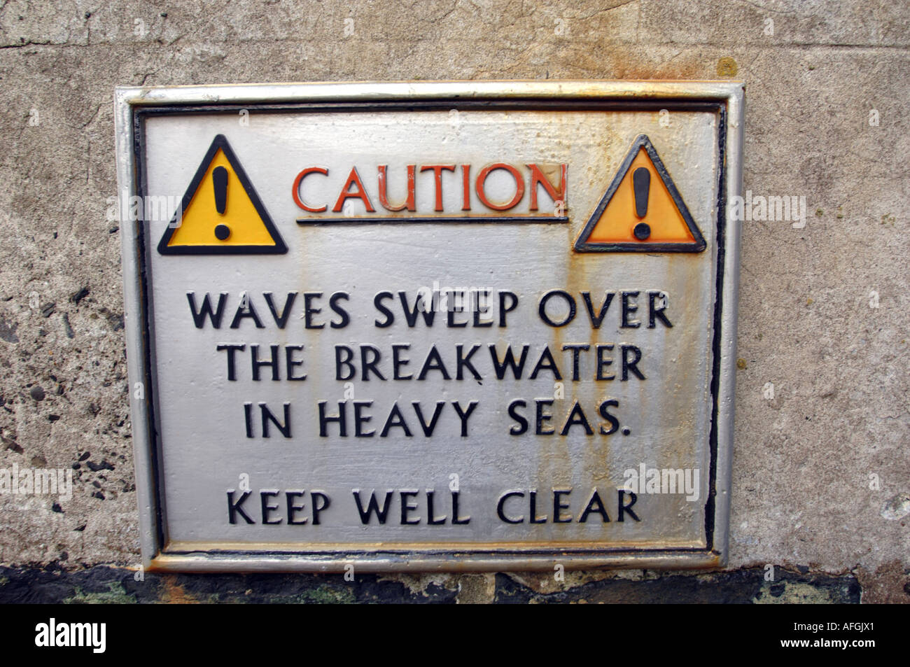 Warning sign about wave danger in harbour wall, UK Stock Photo - Alamy