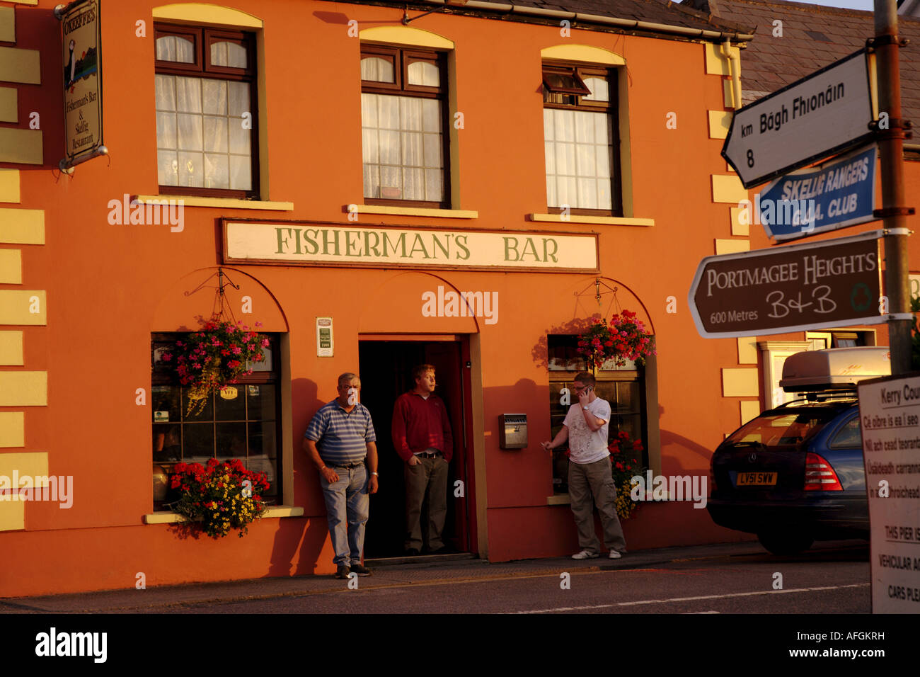 Smokers hang around the door of the Fisherman's Bar, Portmagee, County ...