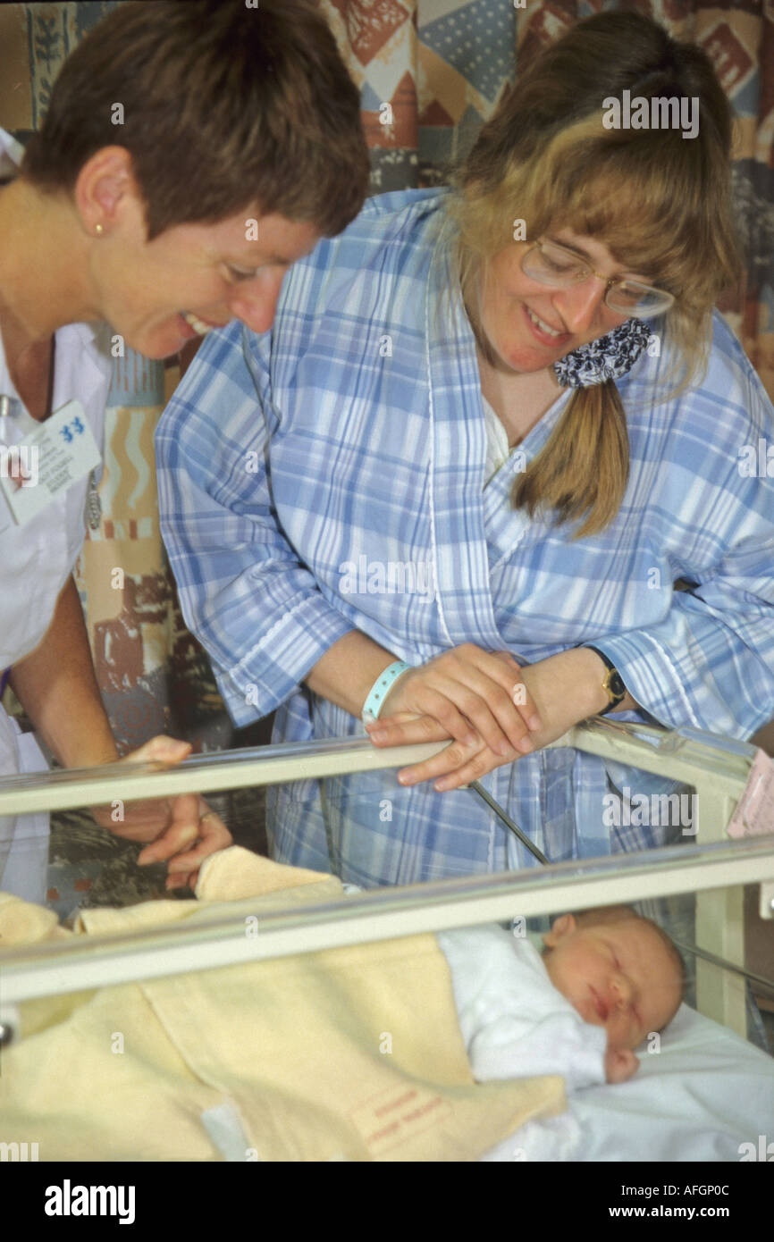 midwife and young mother with new born baby in hospital maternity ward ...