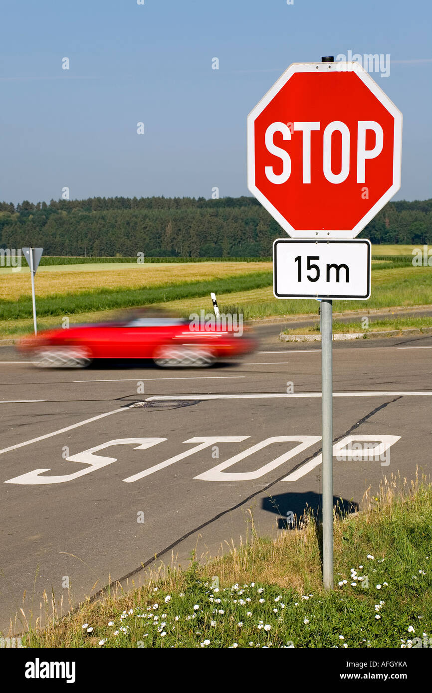 a very fast car passes a crossing with a stop sign Stock Photo - Alamy