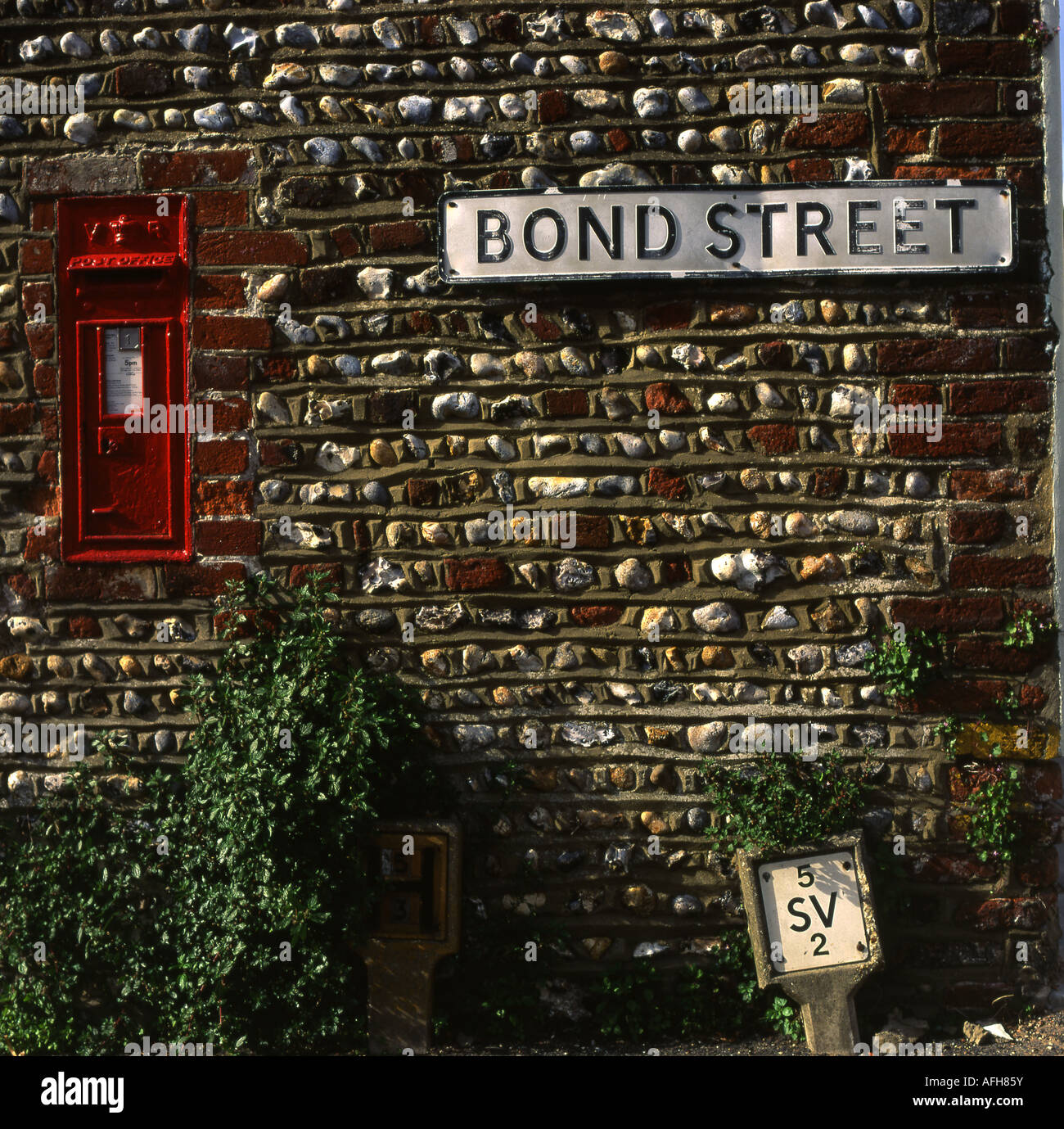 Red Post Box and Bond Street Sign on pebblestone wall Arundel West ...