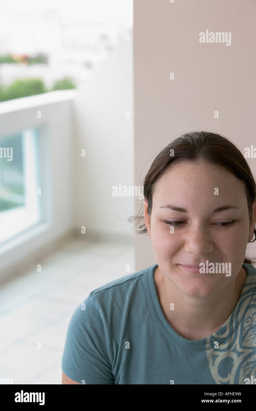 Portrait of young woman sitting by window Stock Photo - Alamy