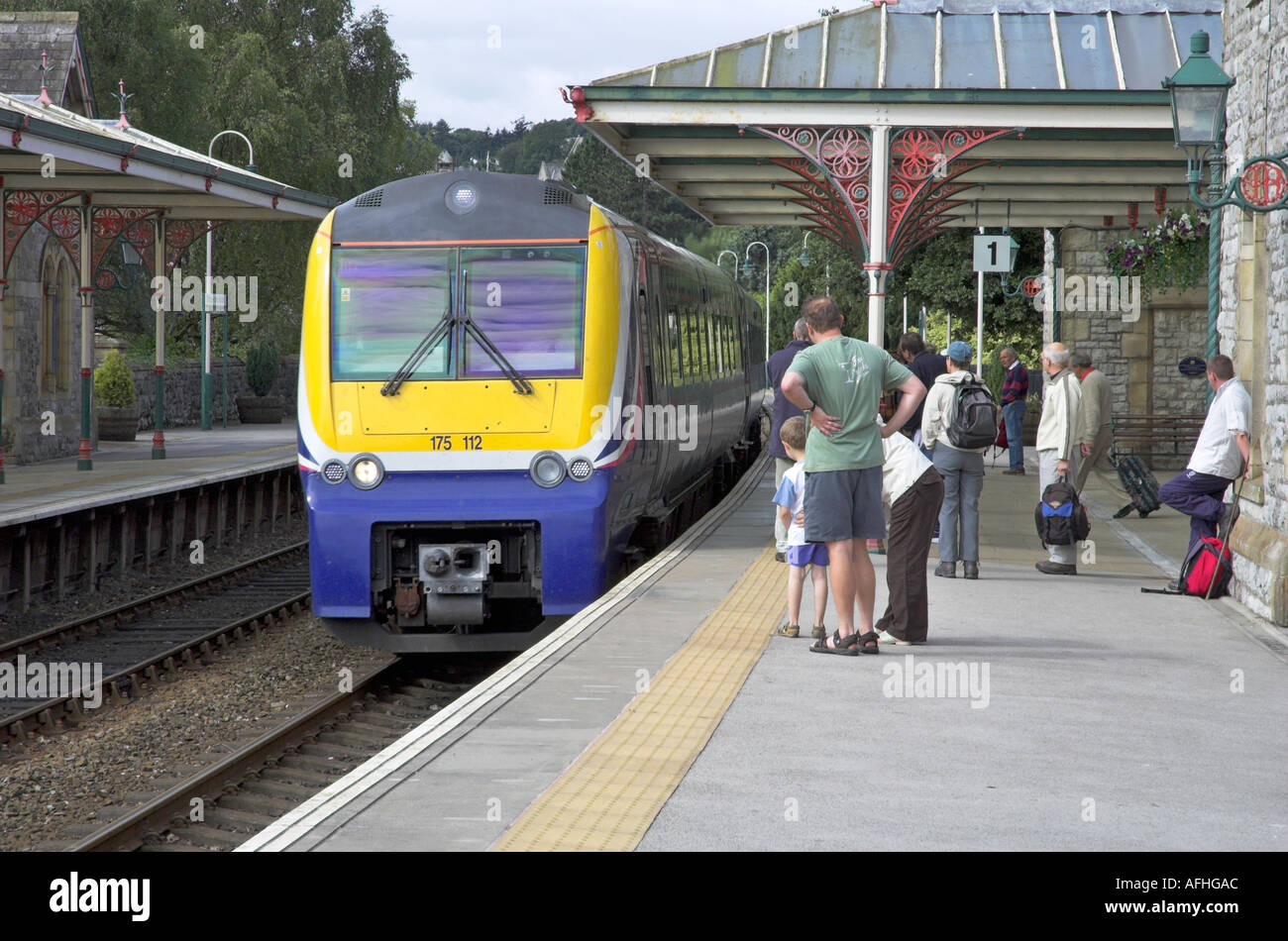 Passengers waiting to start their journey on a railway station platform ...