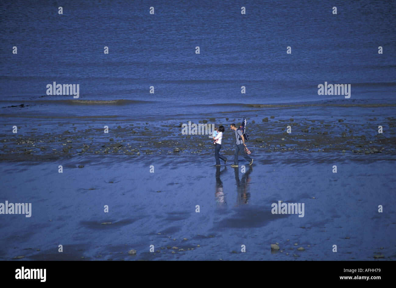 family walking along seashore Stock Photo - Alamy