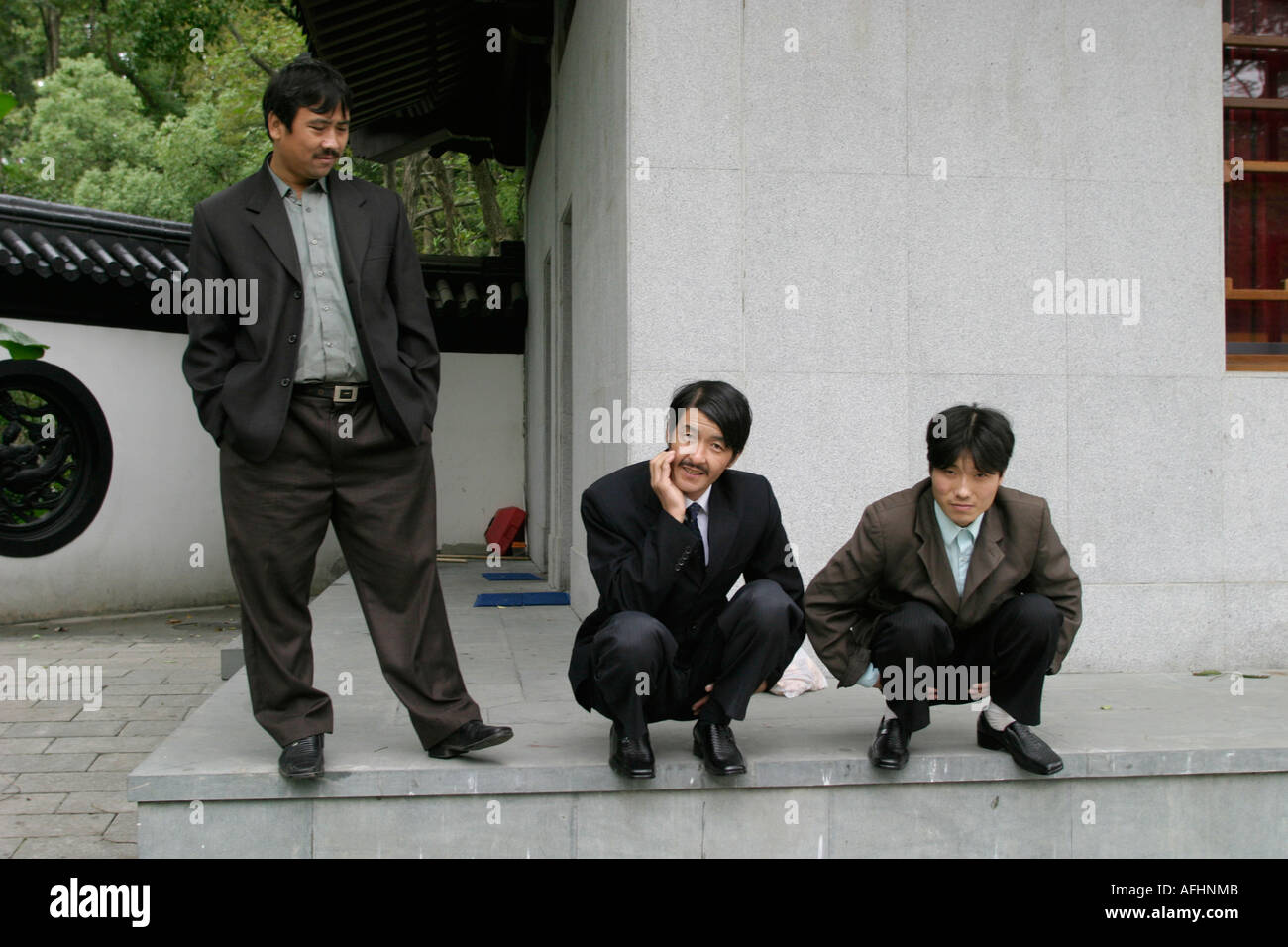 Men sitting on their haunches Stock Photo - Alamy