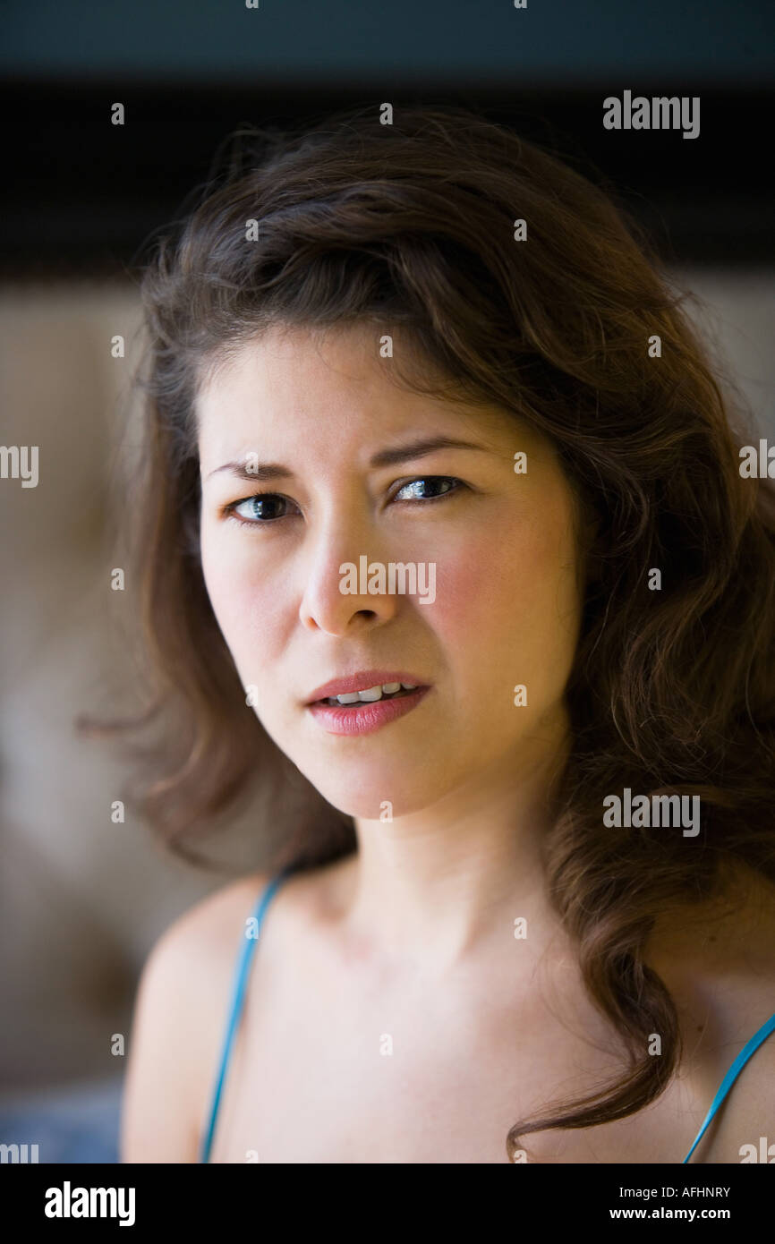 Young woman sitting on edge of bed Stock Photo - Alamy