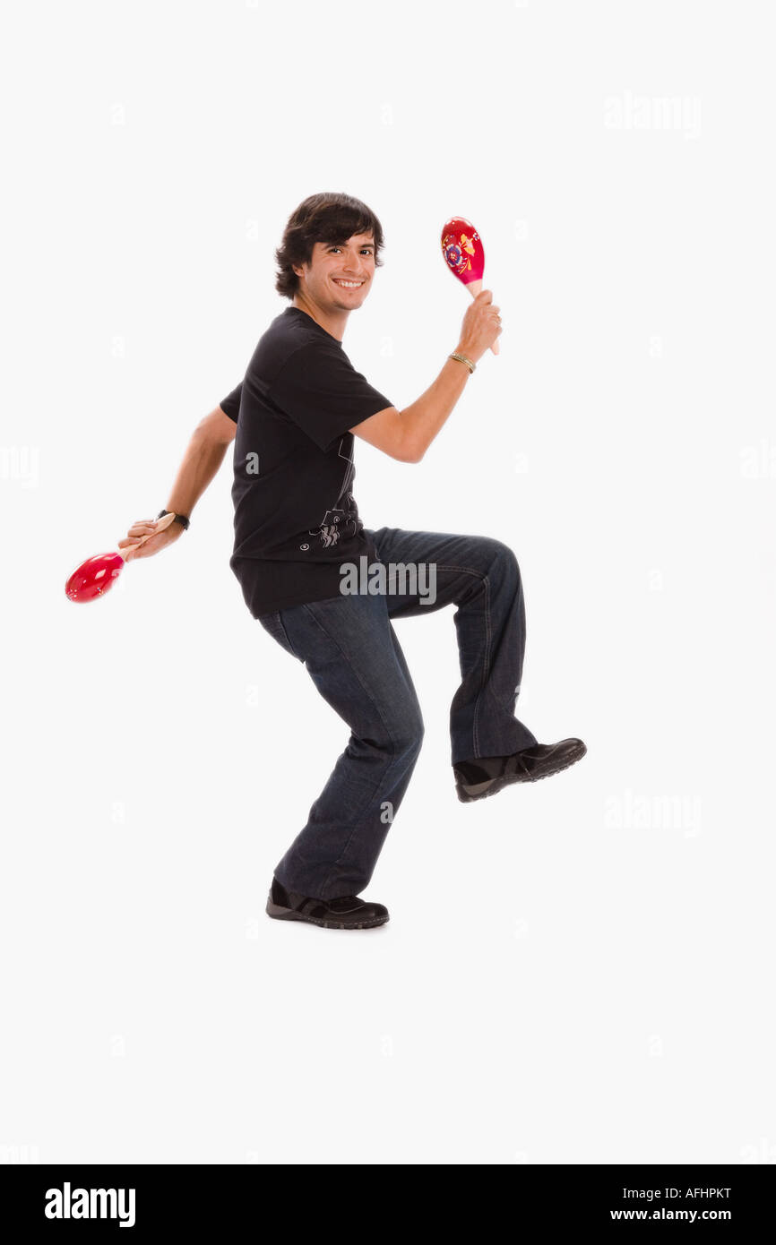 Studio portrait of young man dancing with maracas Stock Photo - Alamy