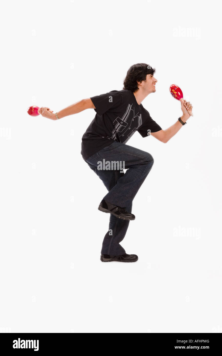 Studio portrait of young man dancing with maracas Stock Photo - Alamy