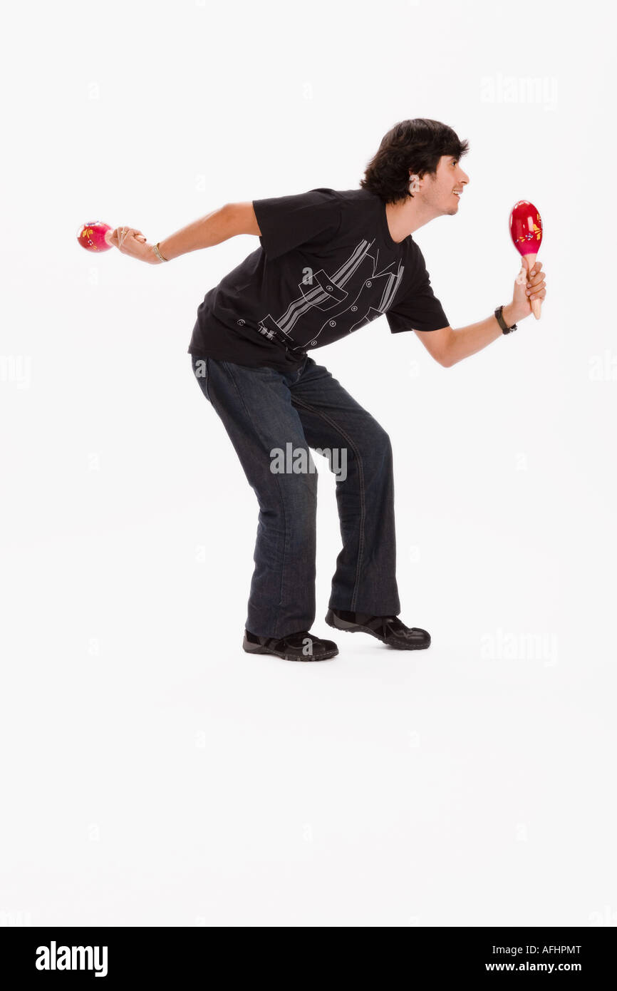 Studio portrait of young man dancing with maracas Stock Photo - Alamy