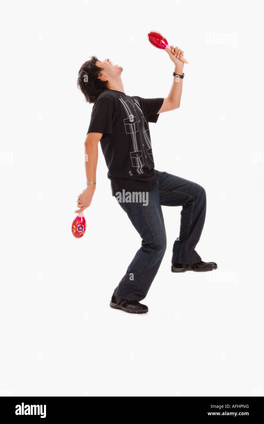 Studio portrait of young man dancing with maracas Stock Photo - Alamy