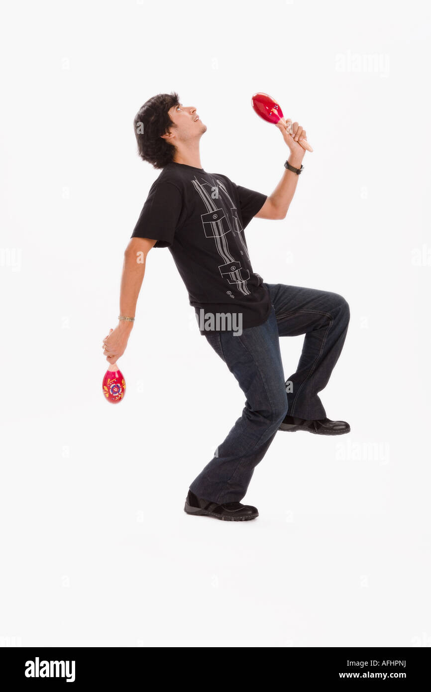 Studio portrait of young man dancing with maracas Stock Photo - Alamy