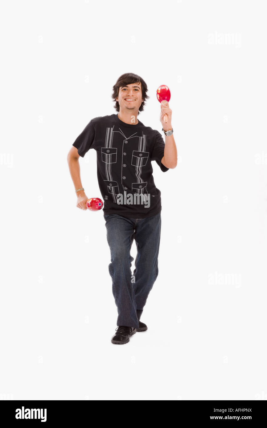 Studio portrait of young man dancing with maracas Stock Photo - Alamy