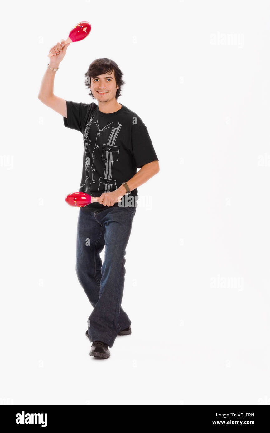 Studio portrait of young man dancing with maracas Stock Photo - Alamy
