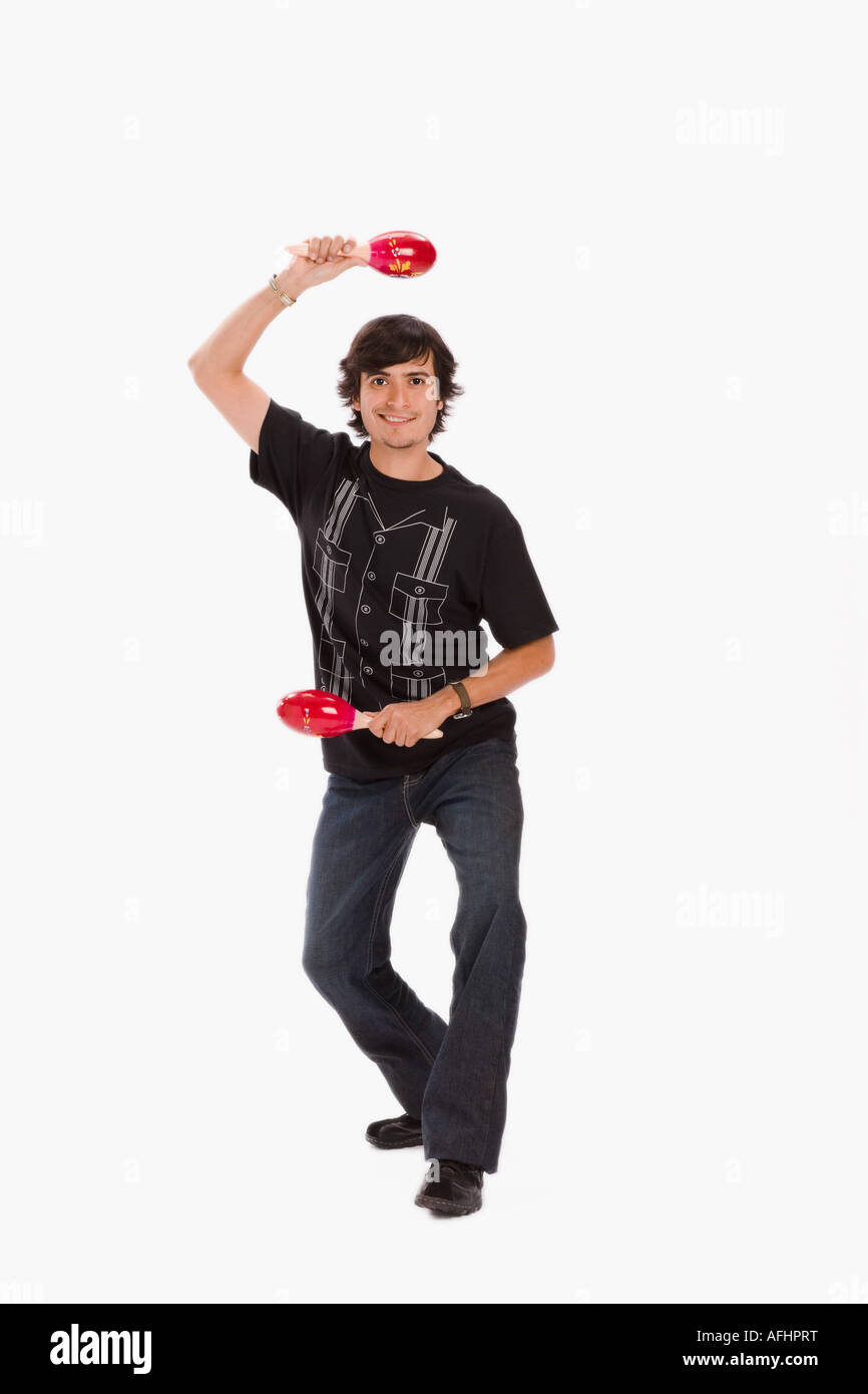 Studio portrait of young man dancing with maracas Stock Photo - Alamy