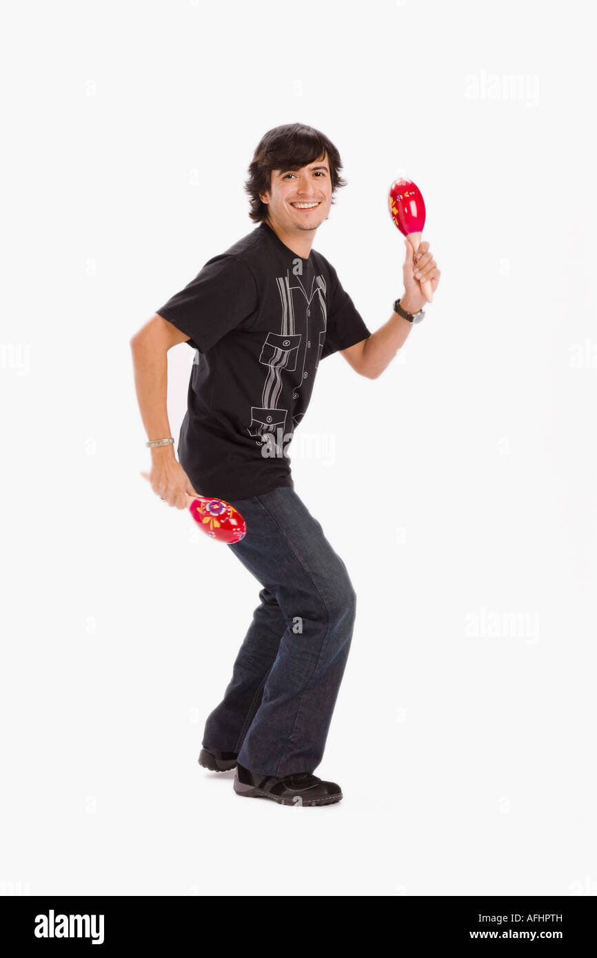 Studio portrait of young man dancing with maracas Stock Photo - Alamy