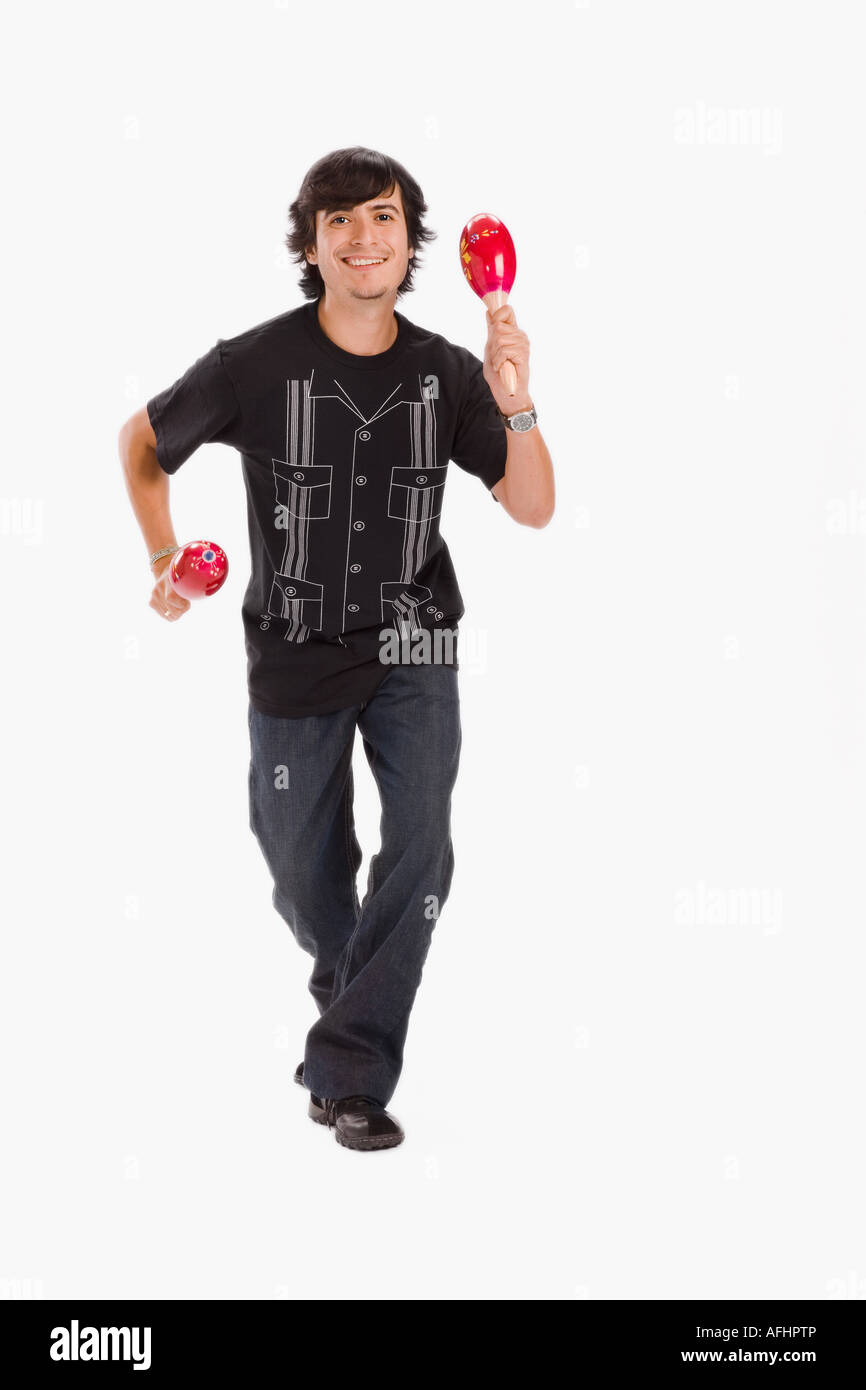 Studio portrait of young man dancing with maracas Stock Photo - Alamy