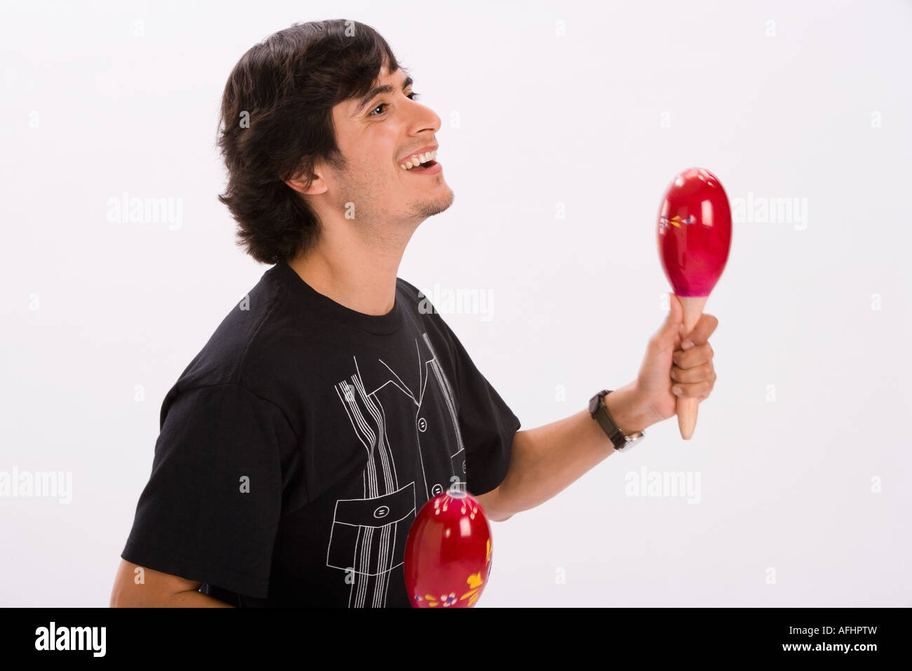 Studio portrait of young man dancing with maracas Stock Photo - Alamy