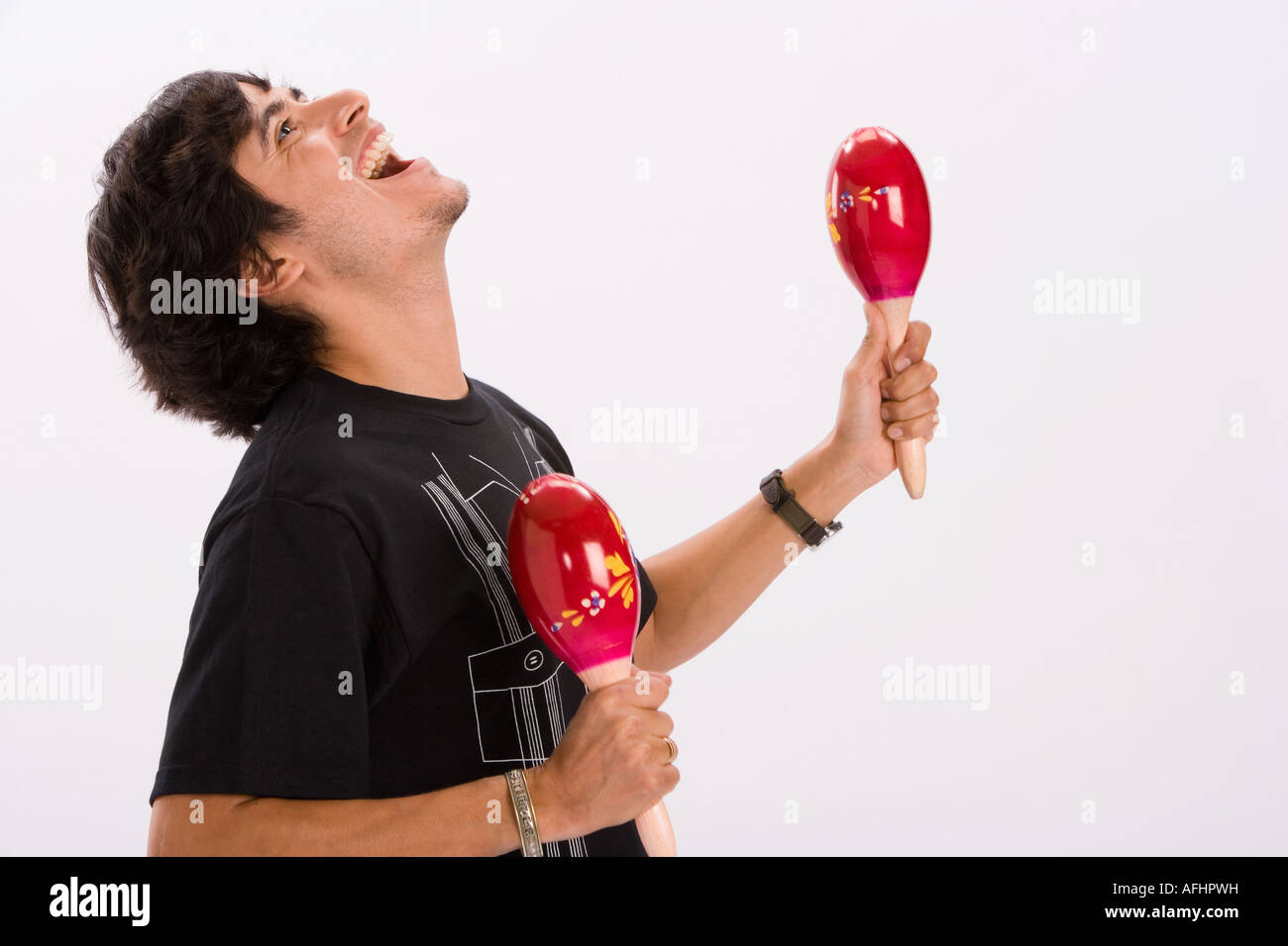 Studio portrait of young man dancing with maracas Stock Photo - Alamy