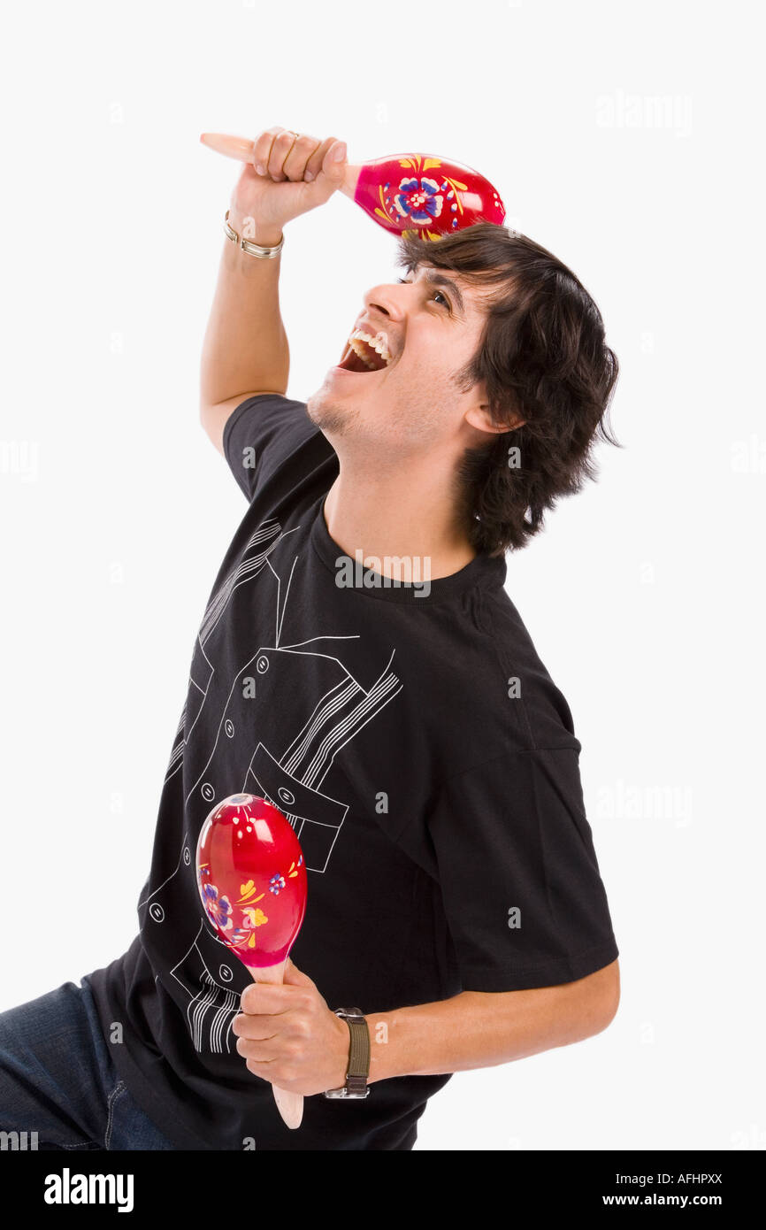 Studio portrait of young man dancing with maracas Stock Photo - Alamy