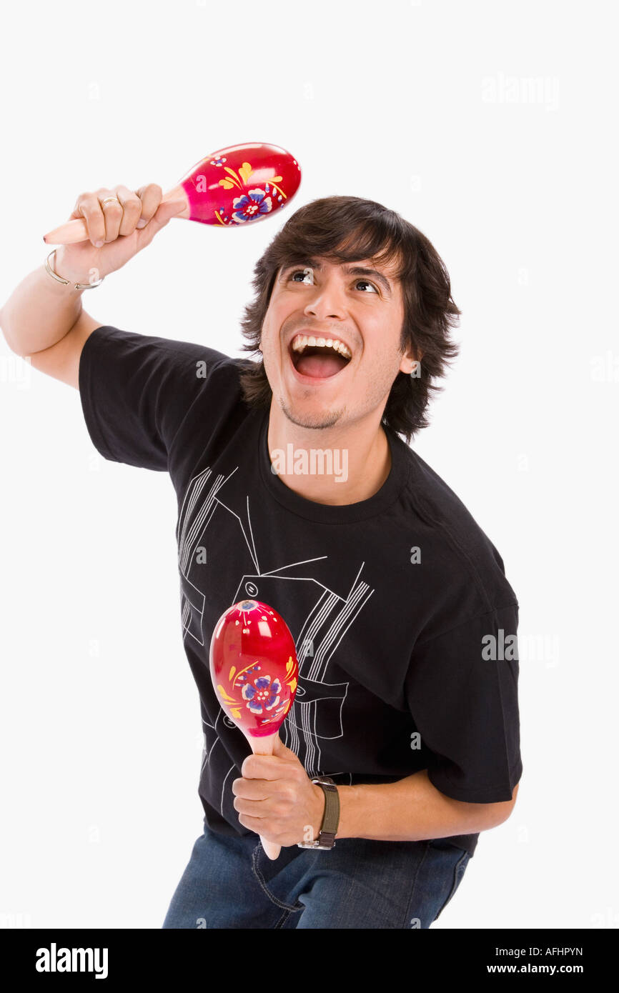 Studio portrait of young man dancing with maracas Stock Photo - Alamy