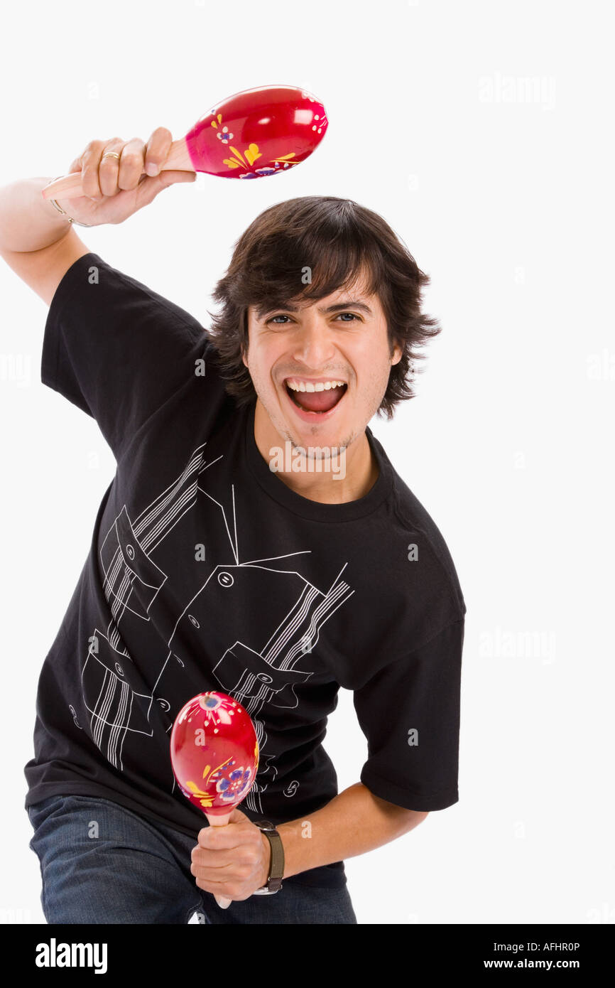 Studio portrait of young man dancing with maracas Stock Photo - Alamy