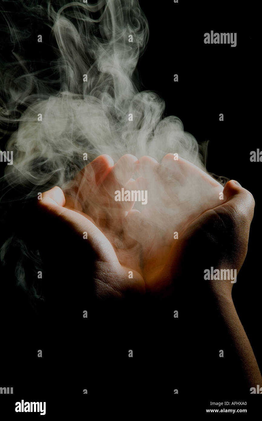 Hands filled with smoke against black background Stock Photo - Alamy