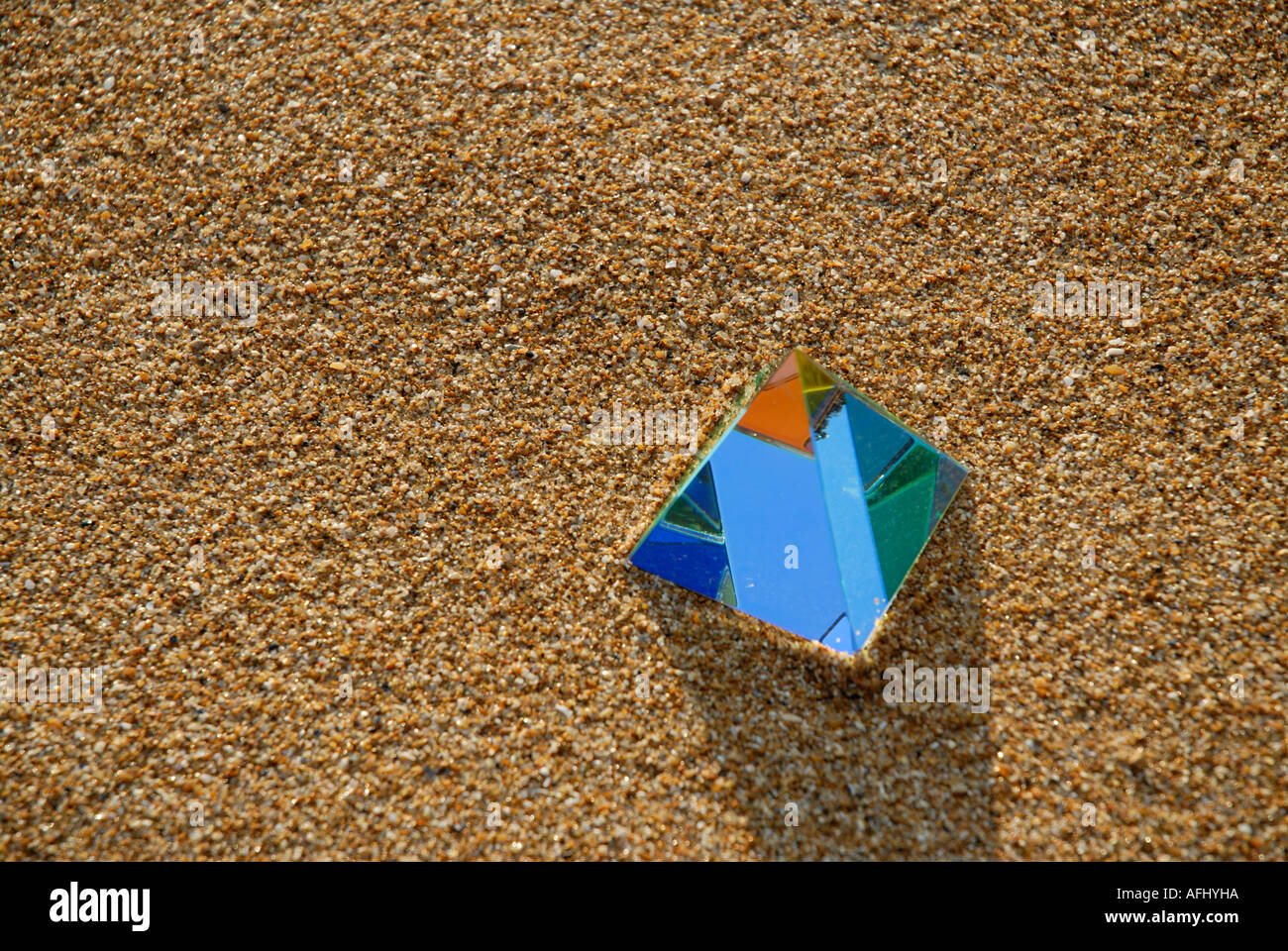 Glass pyramid prism light colour beach sand rock pebble sea seashore ...