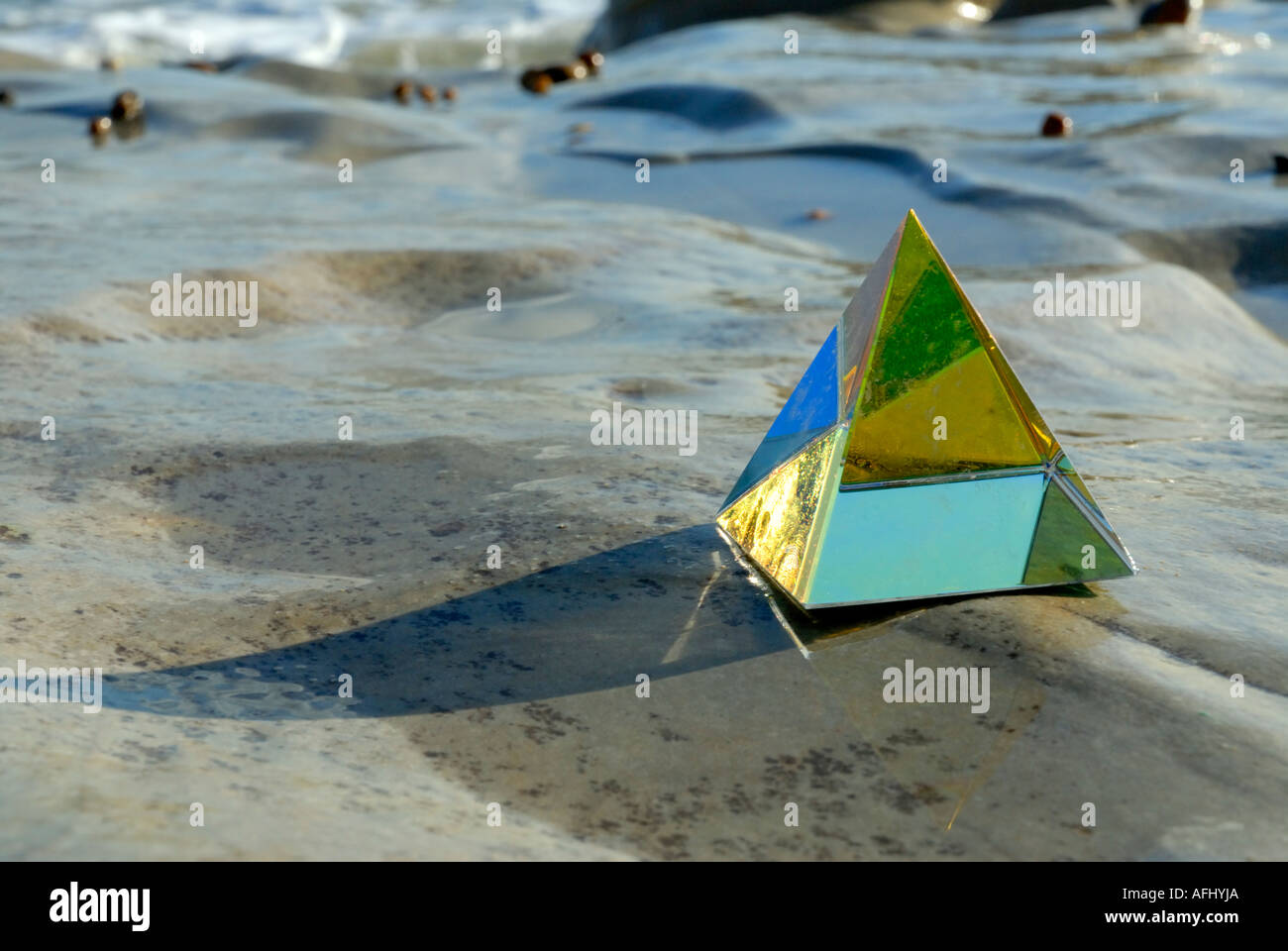 Glass pyramid prism light colour beach sand rock pebble sea seashore ...