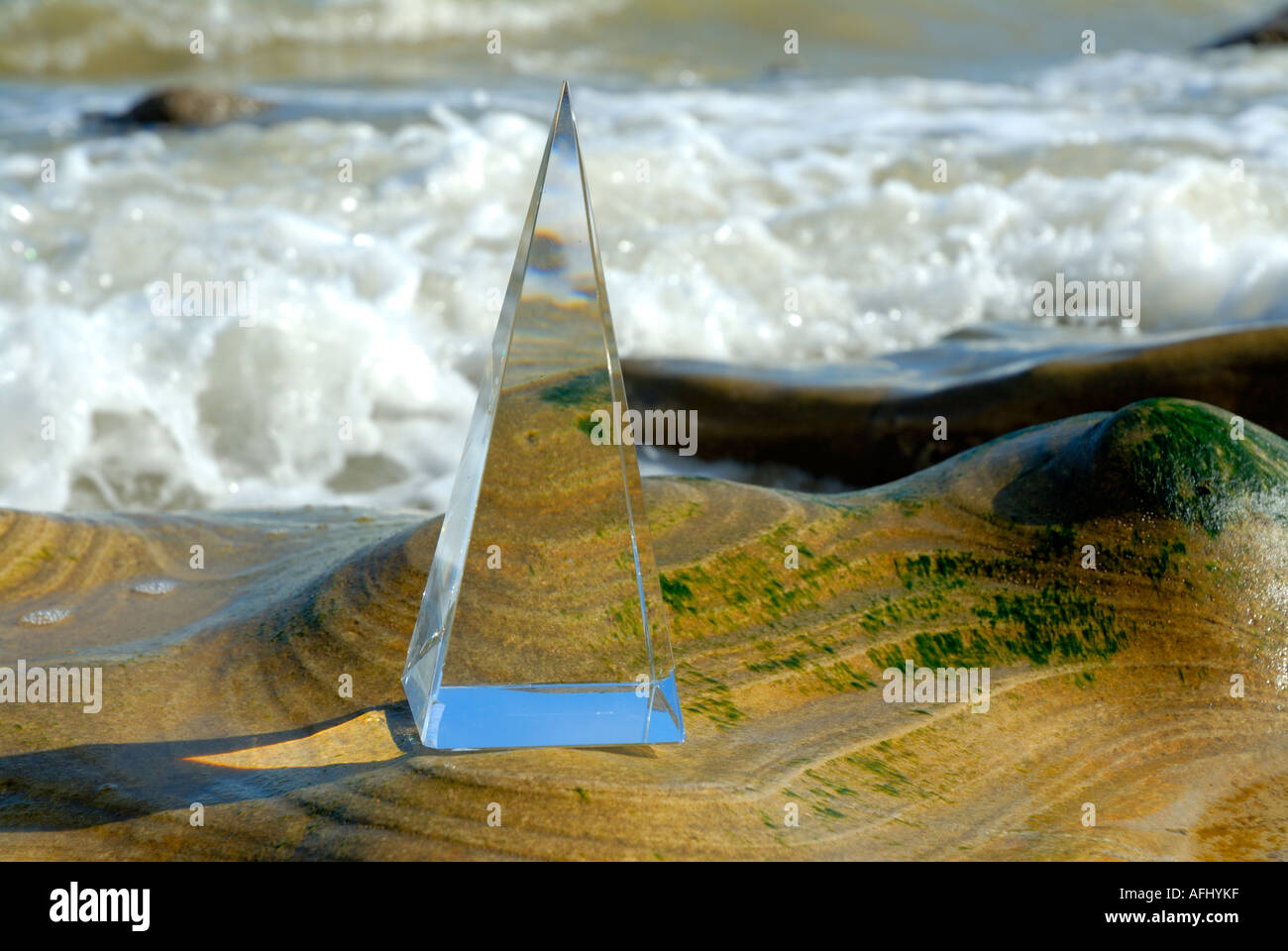 Glass pyramid prism light colour beach sand rock pebble sea seashore ...