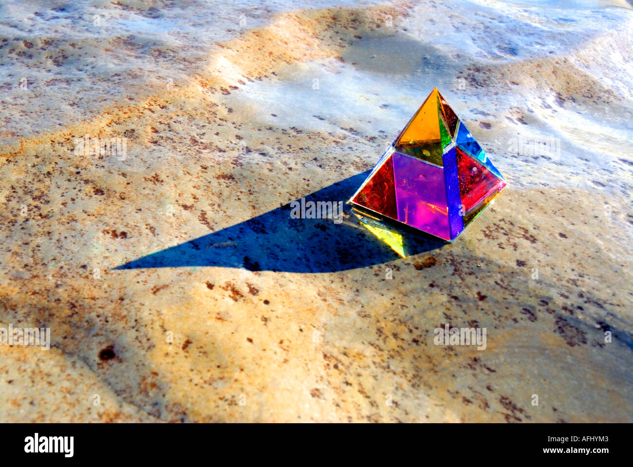 Glass pyramid prism light colour beach sand rock pebble sea seashore ...