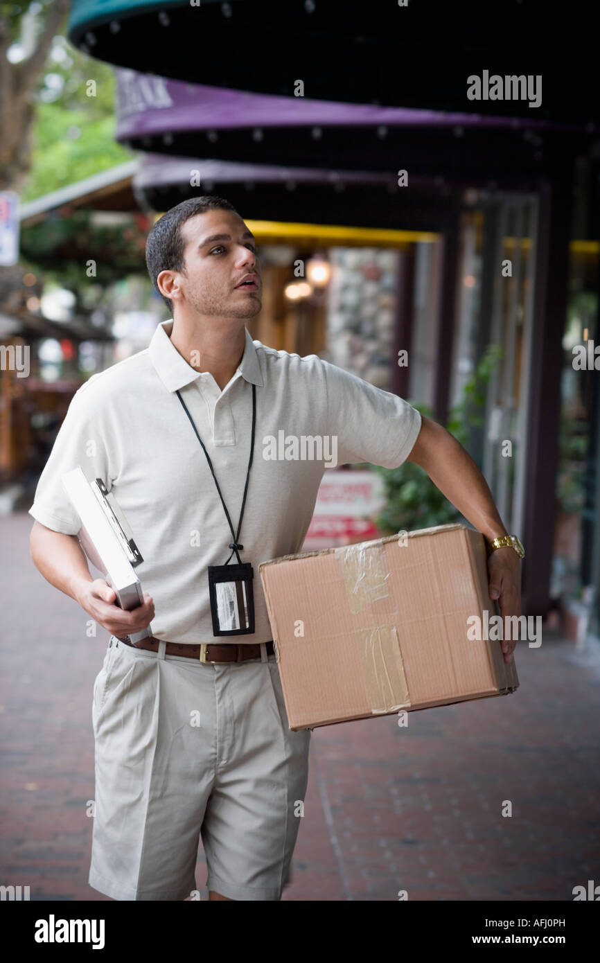Delivery man carrying large box Stock Photo - Alamy