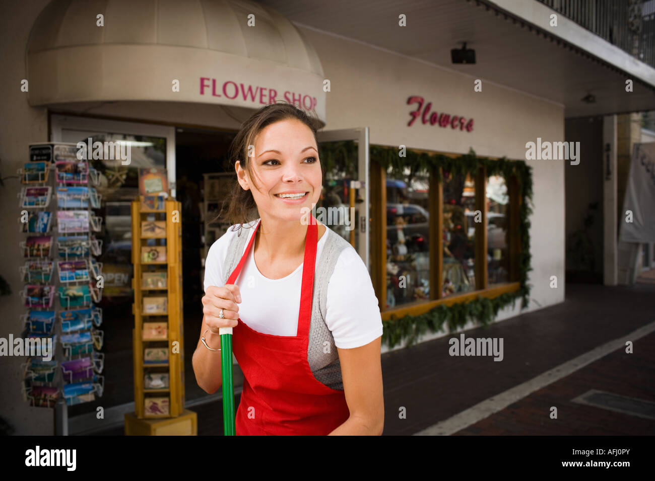 Young woman sweeps outside flower shop Stock Photo - Alamy