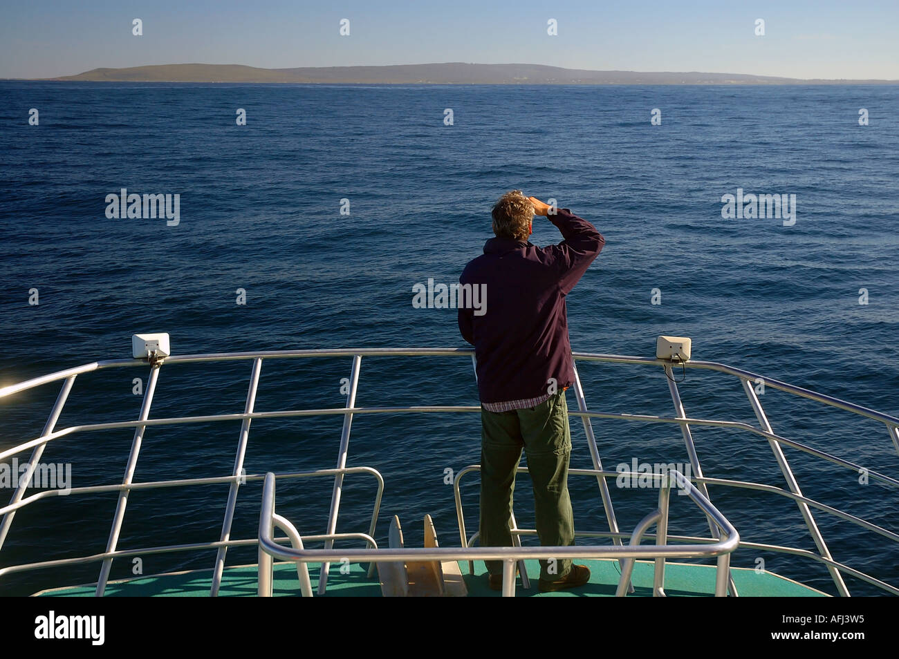 Man looking out to sea on bow of large boat Stock Photo - Alamy