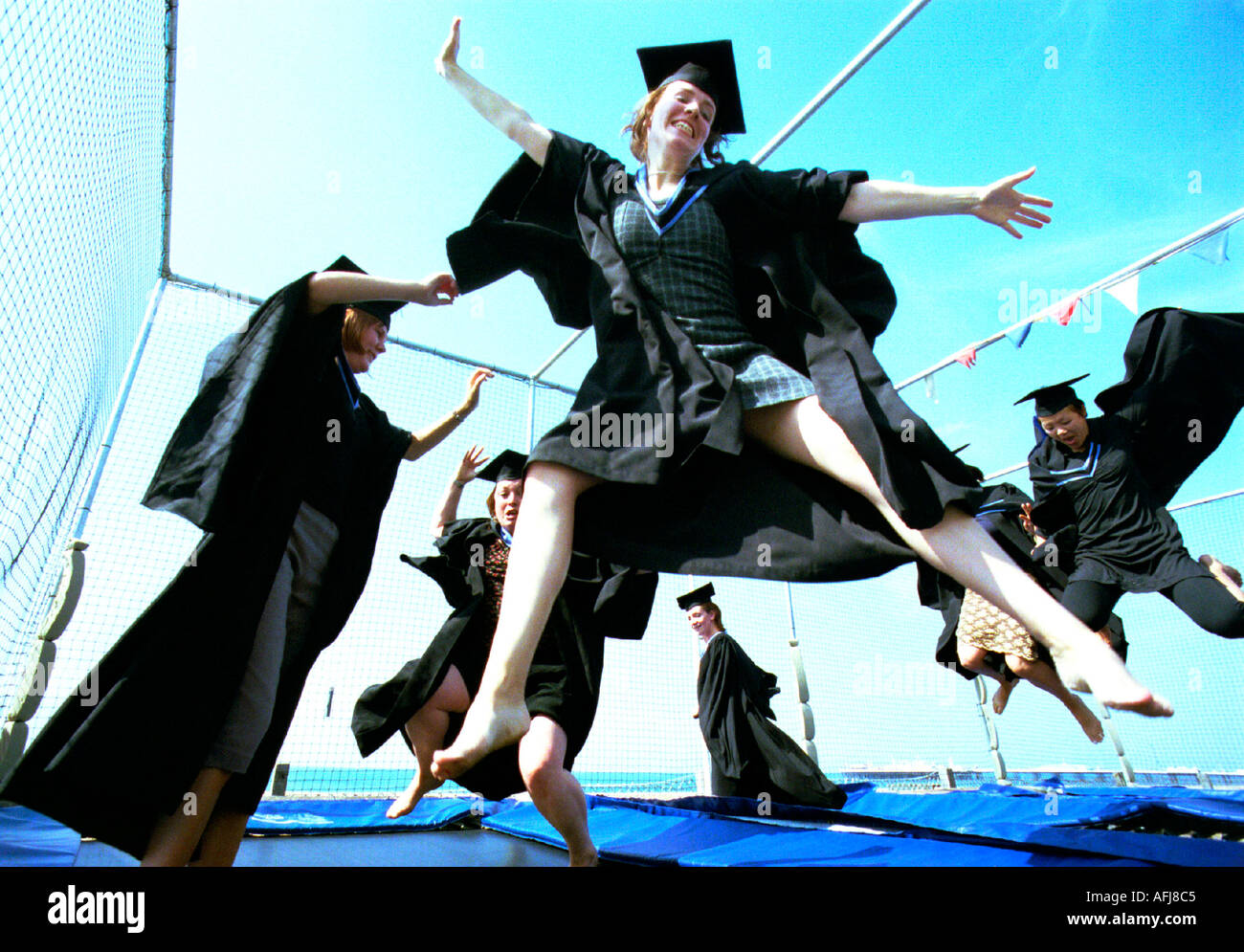 University graduates celebrate their graduation on a trampoline Stock ...