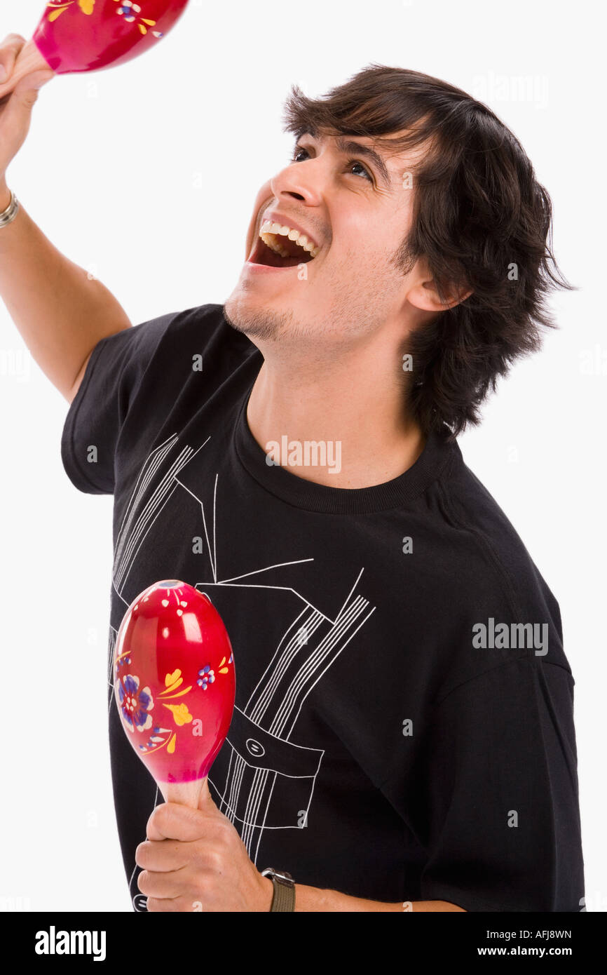 Studio portrait of young man dancing with maracas Stock Photo - Alamy