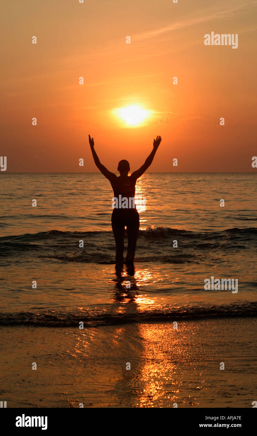 a skinhead girl throwing water at the sun in goa india Stock Photo - Alamy