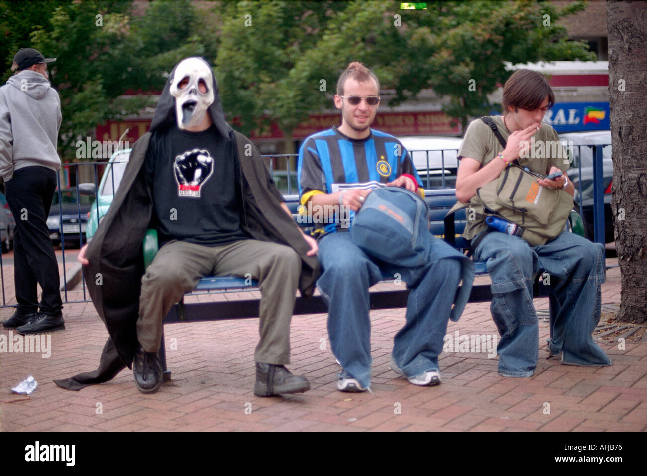 Three young men sitting on a street bench during a protest march in ...