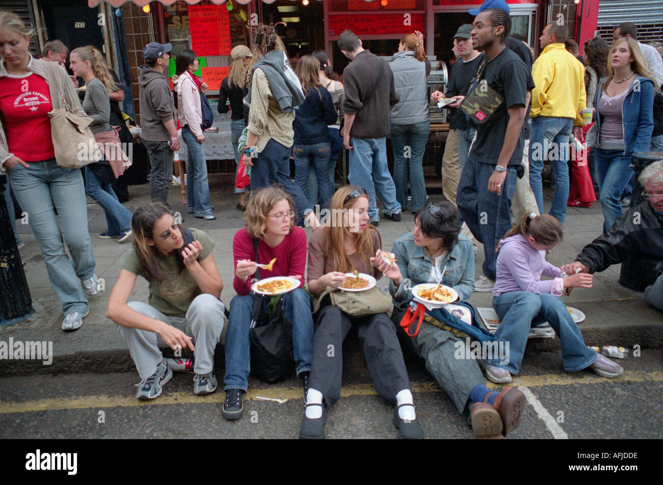 Sitting on pavement eating street food during of Notting Hill Gate ...