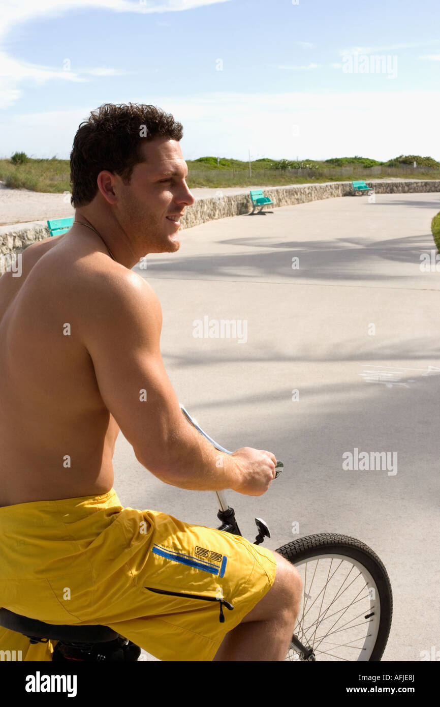 Young man riding bicycle on beach Stock Photo - Alamy