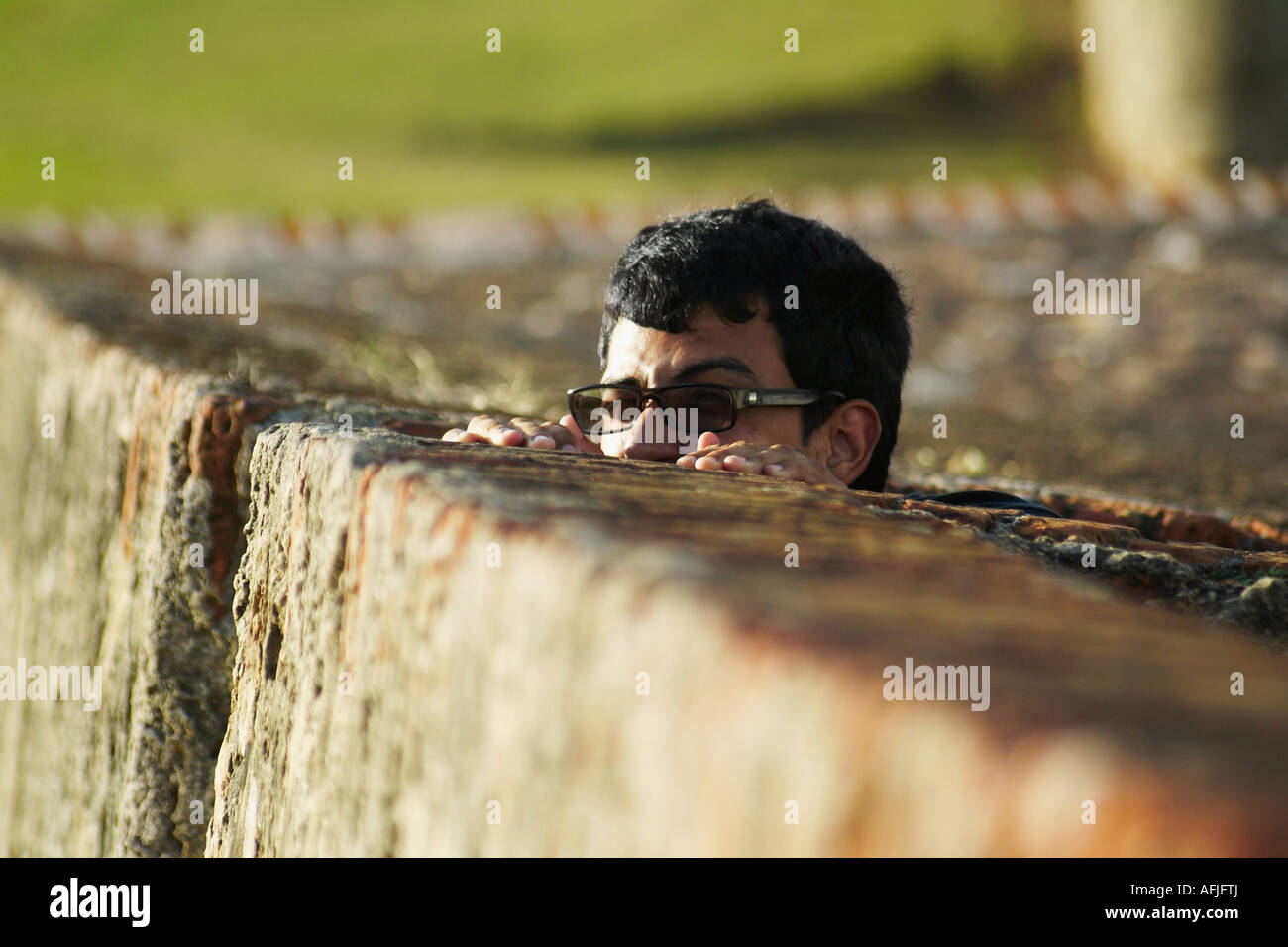 Young man peeking over fence Stock Photo - Alamy