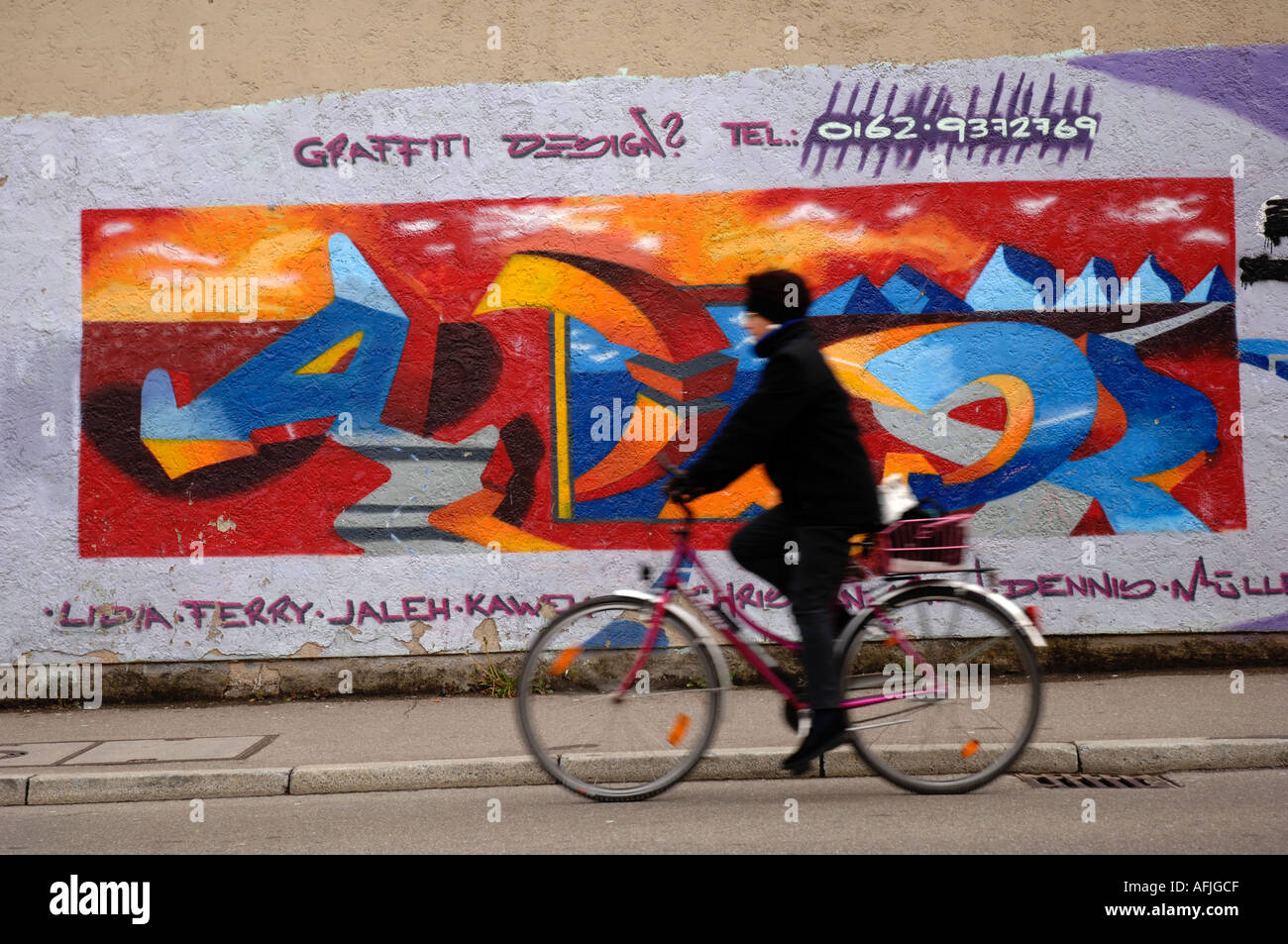 A cyclist goes past graffiti painted on a wall Stock Photo - Alamy