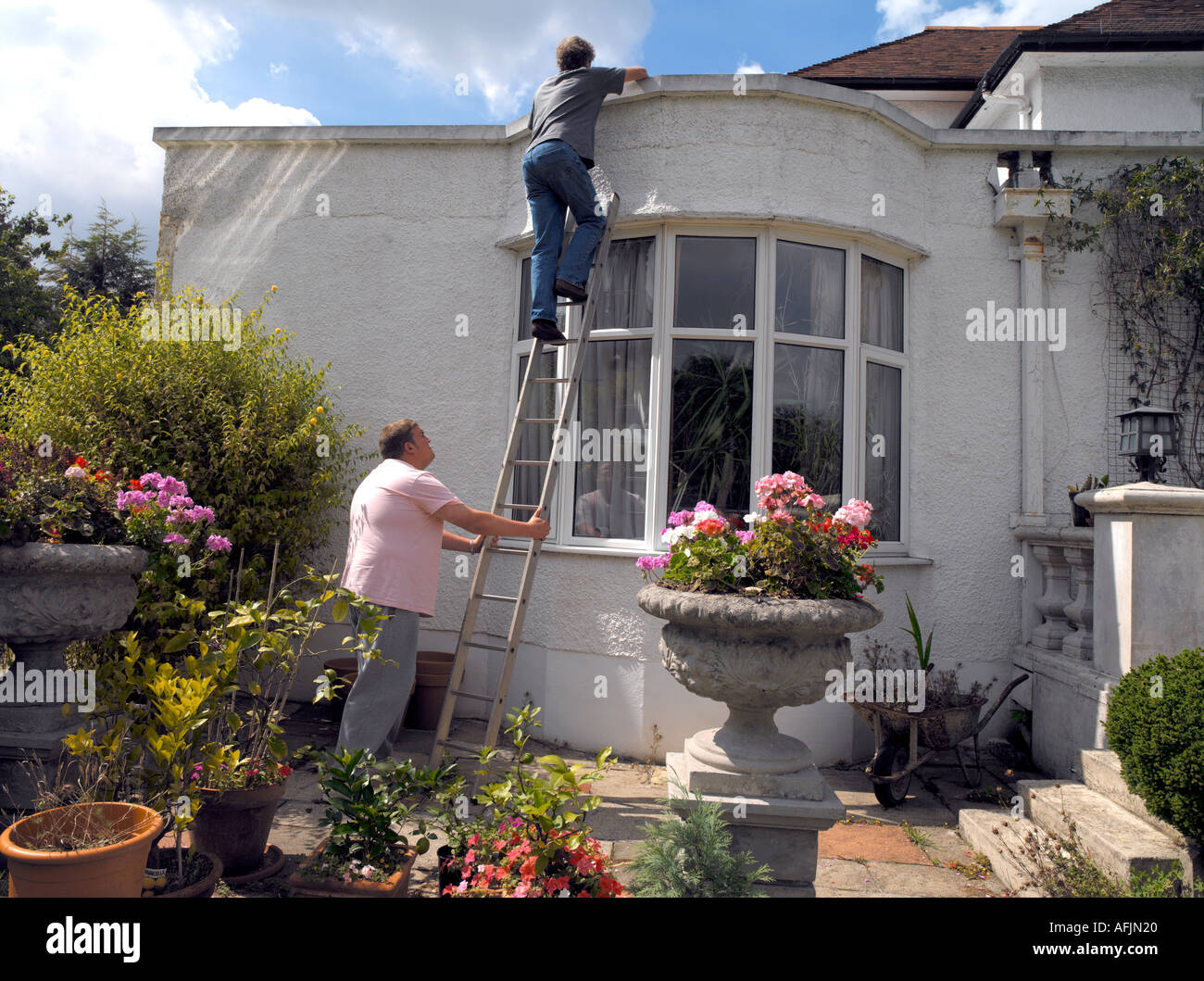 Two Men on a Ladder One on Top of Ladder Looking at the Roof Other ...