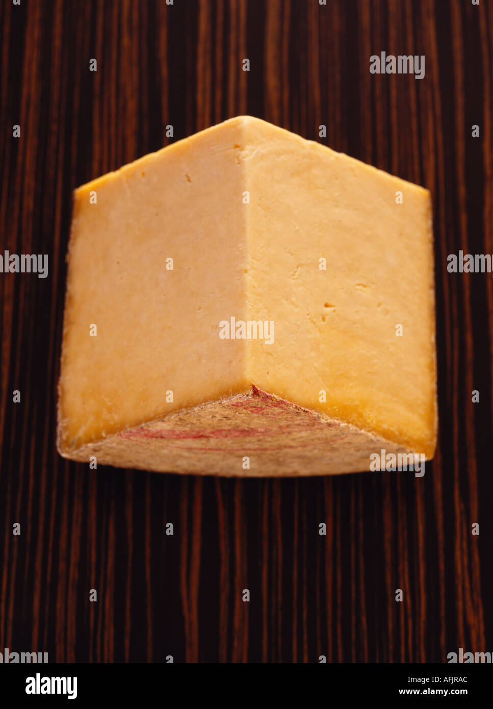 Wedge of red cheddar cheese on brown formica background Stock Photo - Alamy